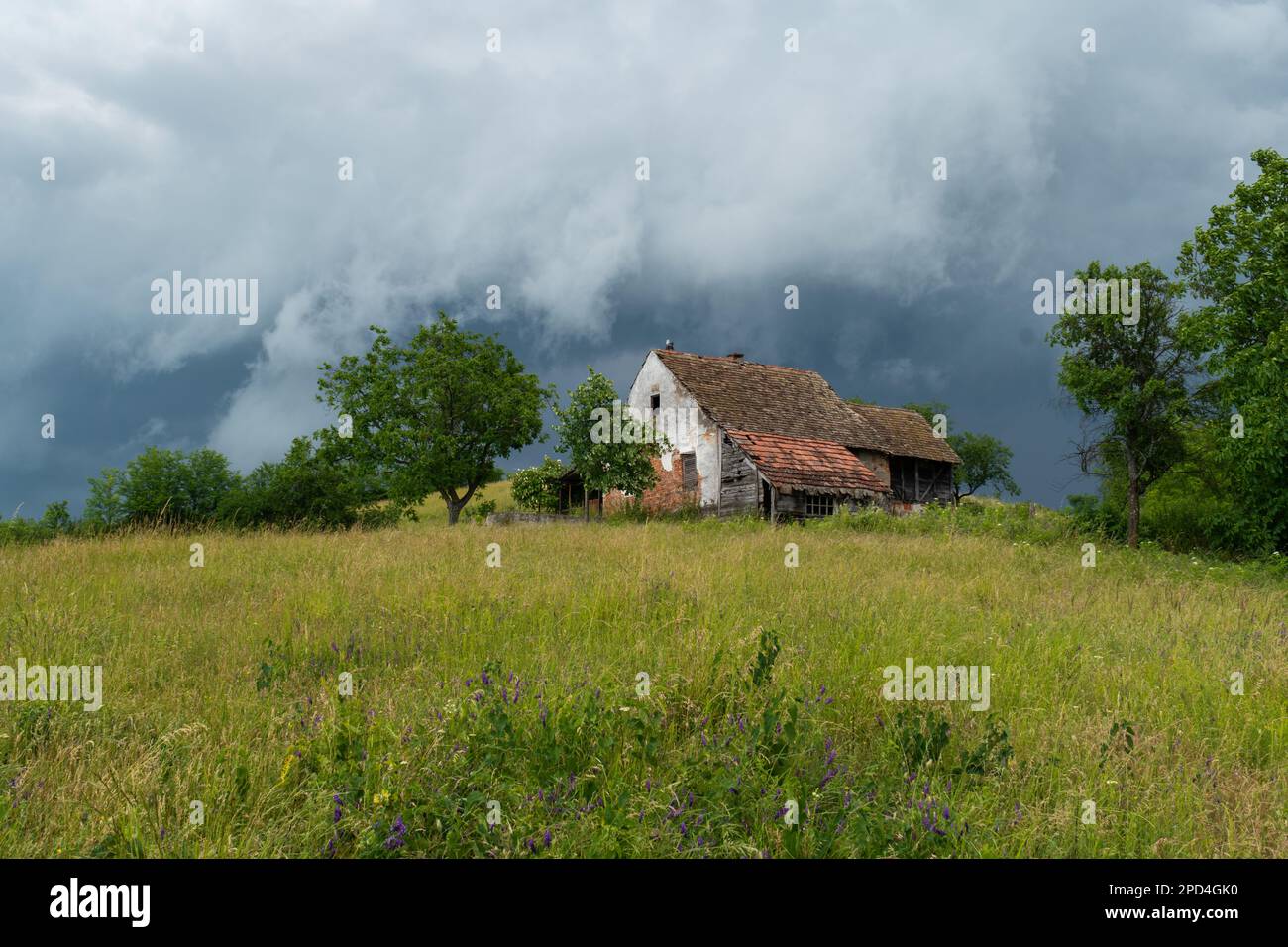 Storm clouds above abandoned countryside house, dark dramatic clouds above empty deserted ...