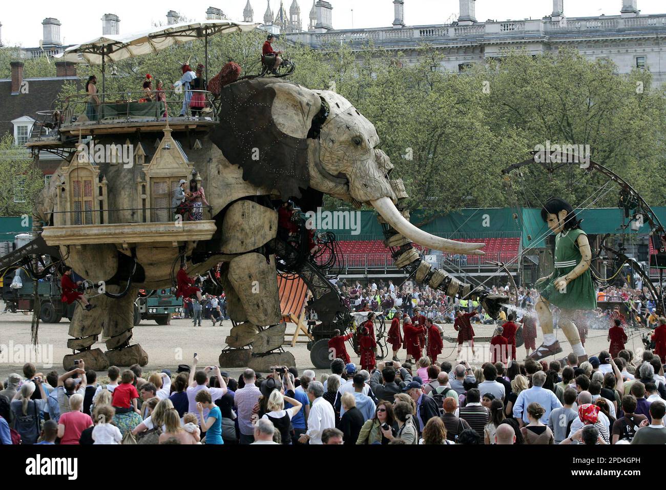 A giant mechanical elephant greets the giant puppet girl in an outdoor ...
