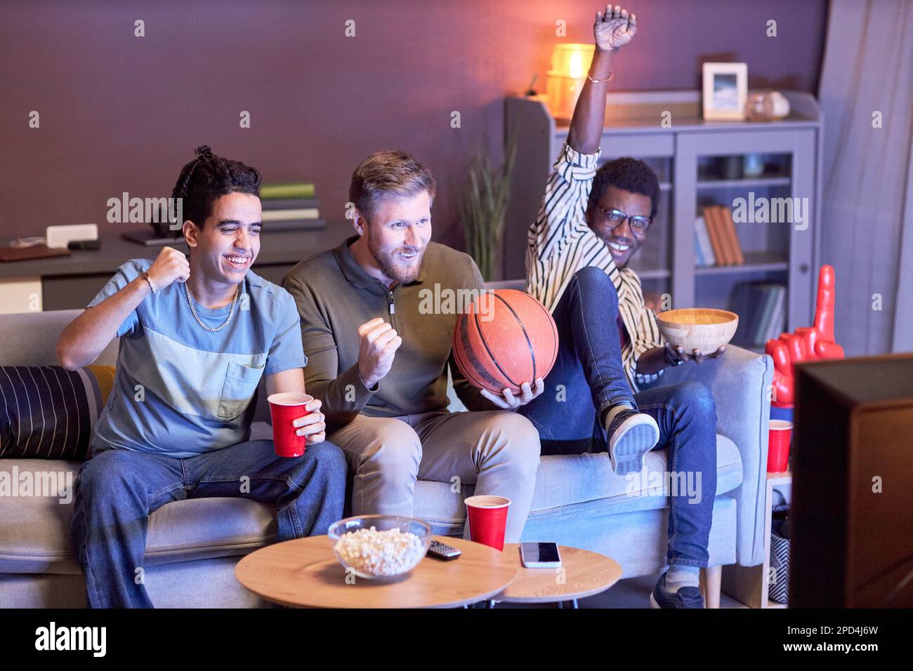 Diverse group of emotional sports fans watching basketball match at ...