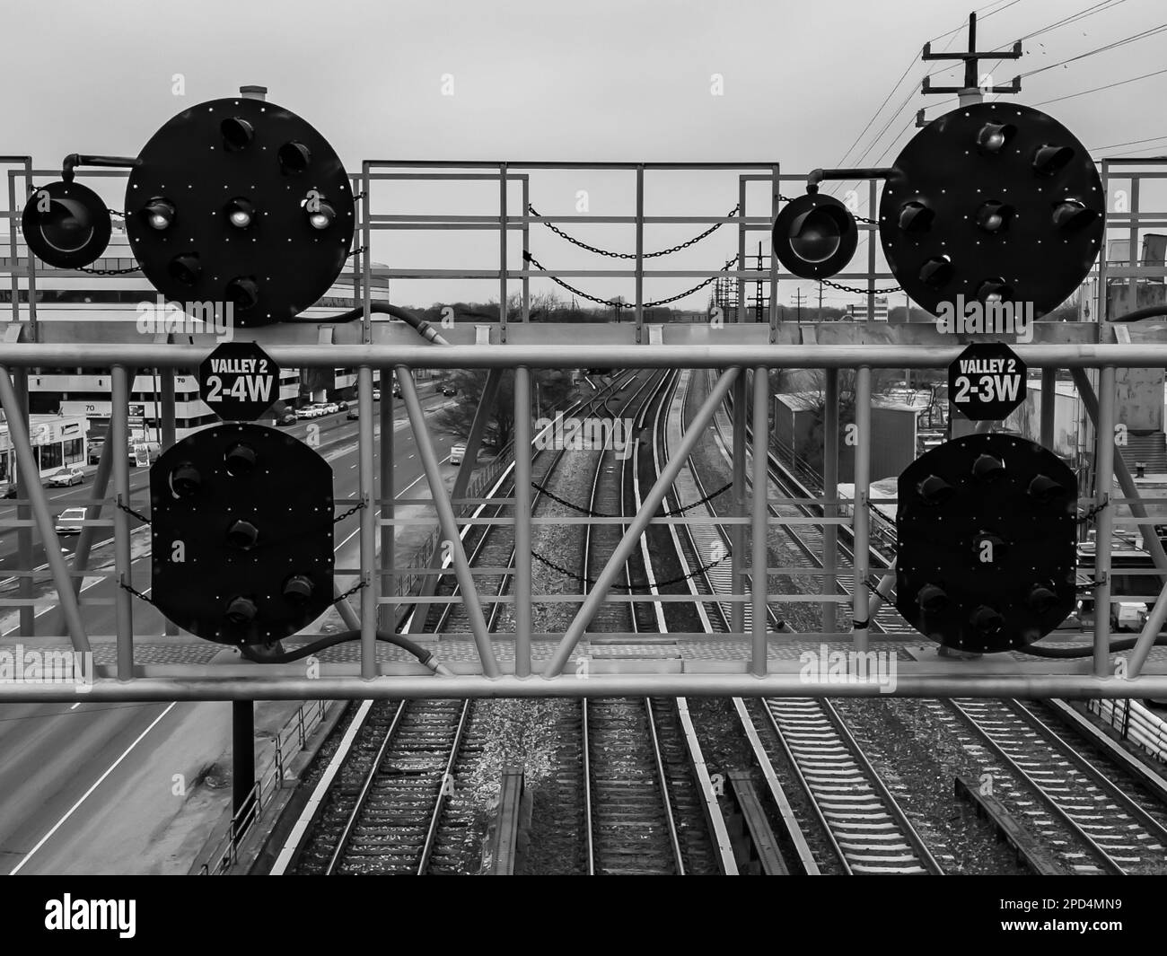 A grayscale shot of a train signal platform over empty train tracks ...