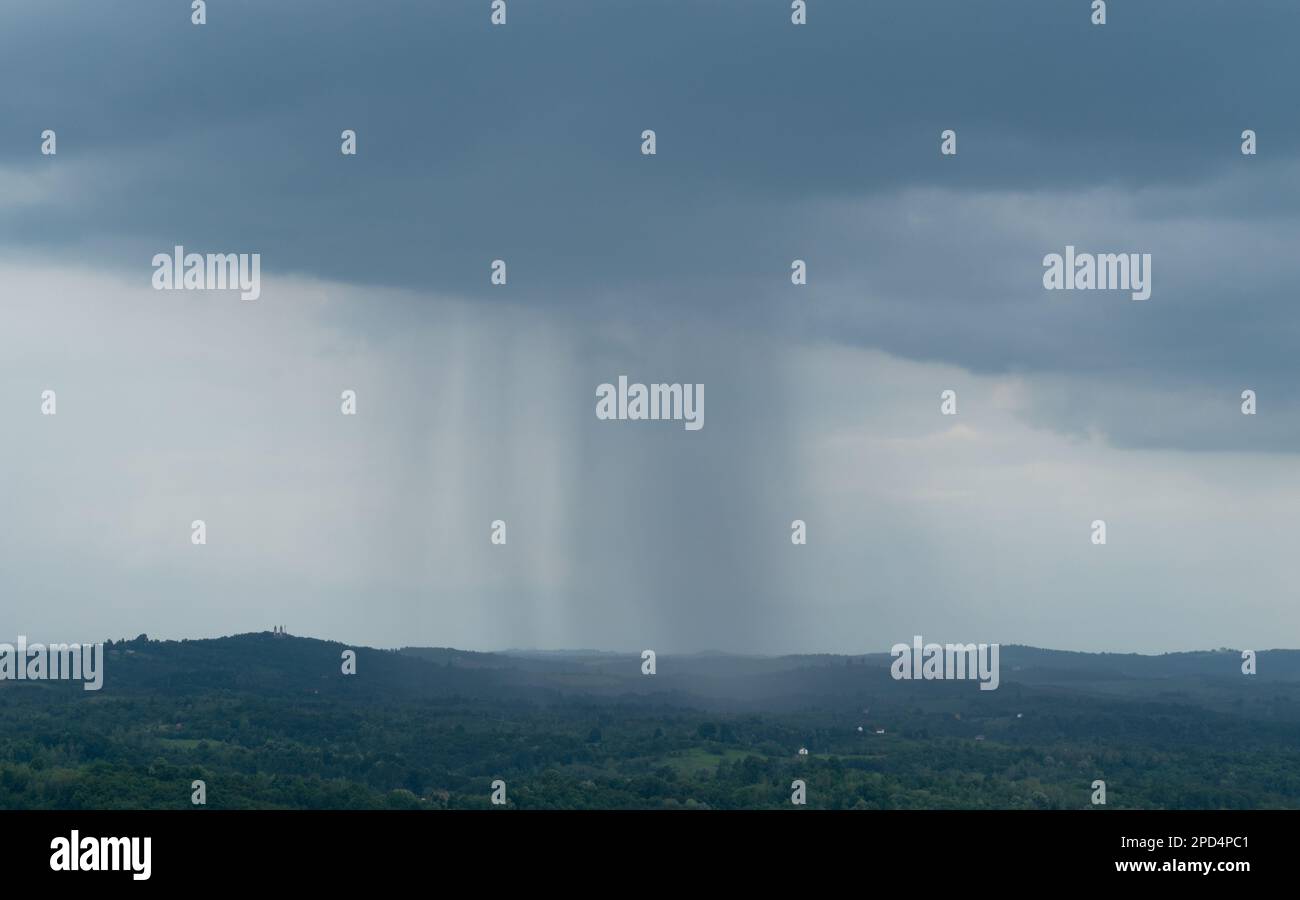 Dark cloud with rain curtain over countryside, cloudburst over hilly ...