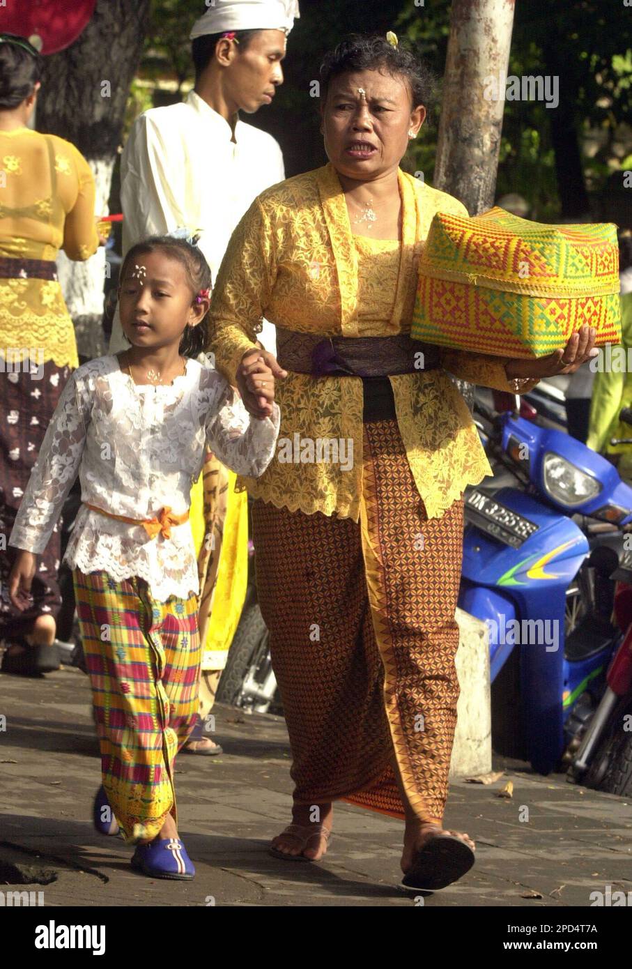 Balinese family in traditional dress walk to a temple for pray during a ...