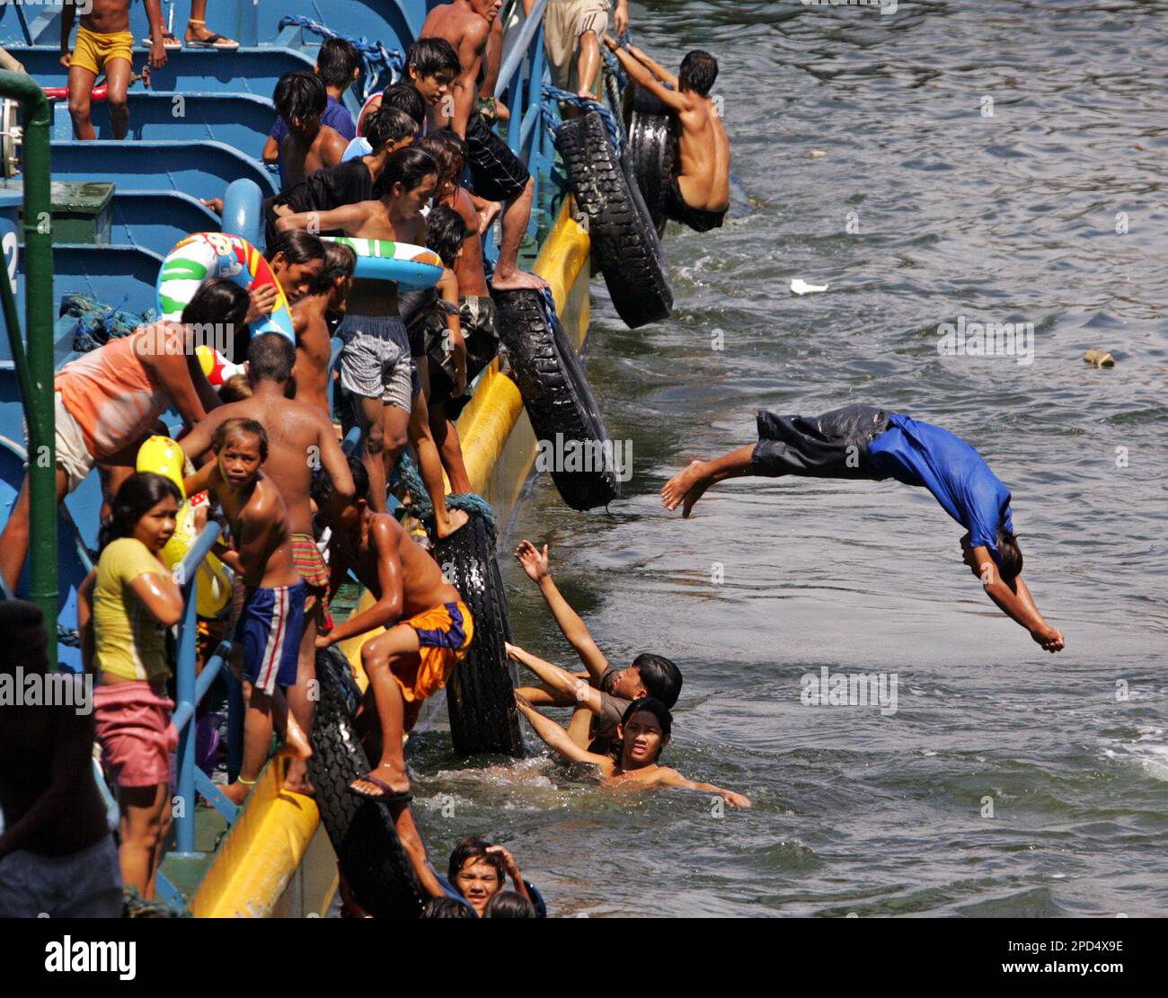 Manila's street children climb onto a slow-passing oil barge to dive ...