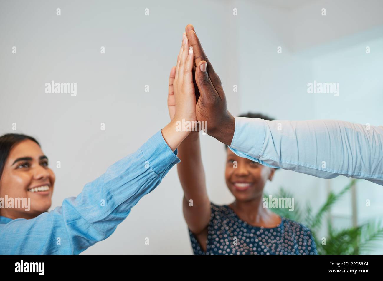 Three colleagues give high five in office, celebrate success, happy ...
