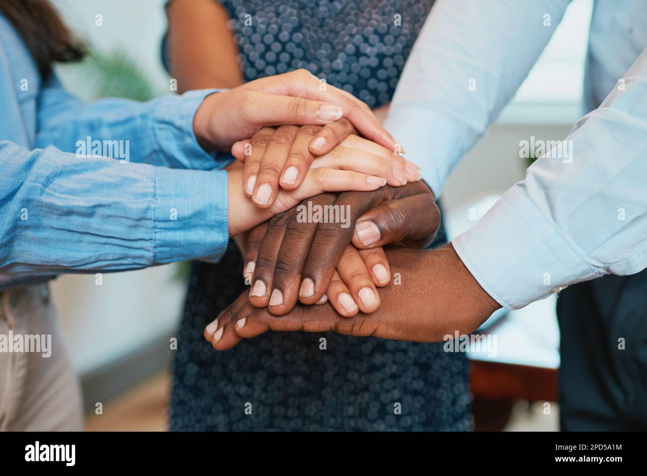 Close up of pile of hands stacked together, corporate office setting ...