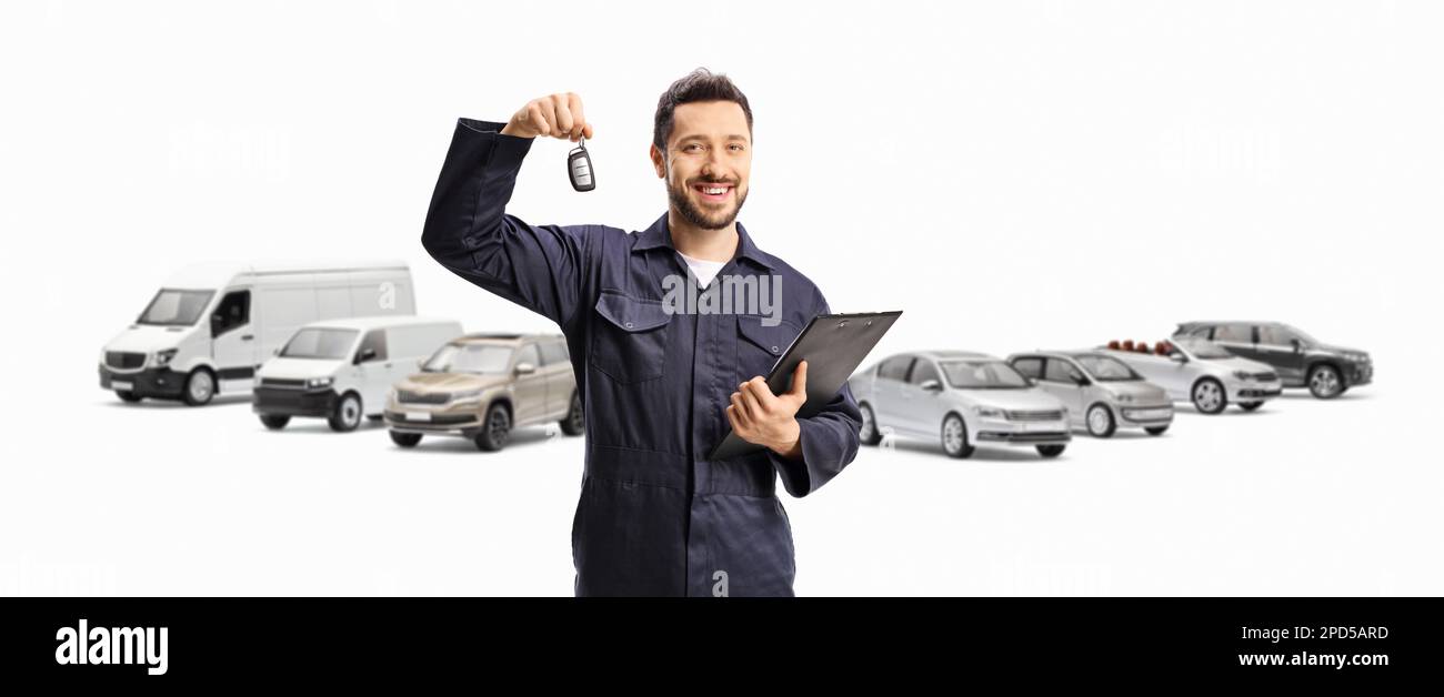 Auto mechanic holding car key in front of different parked vehicles ...