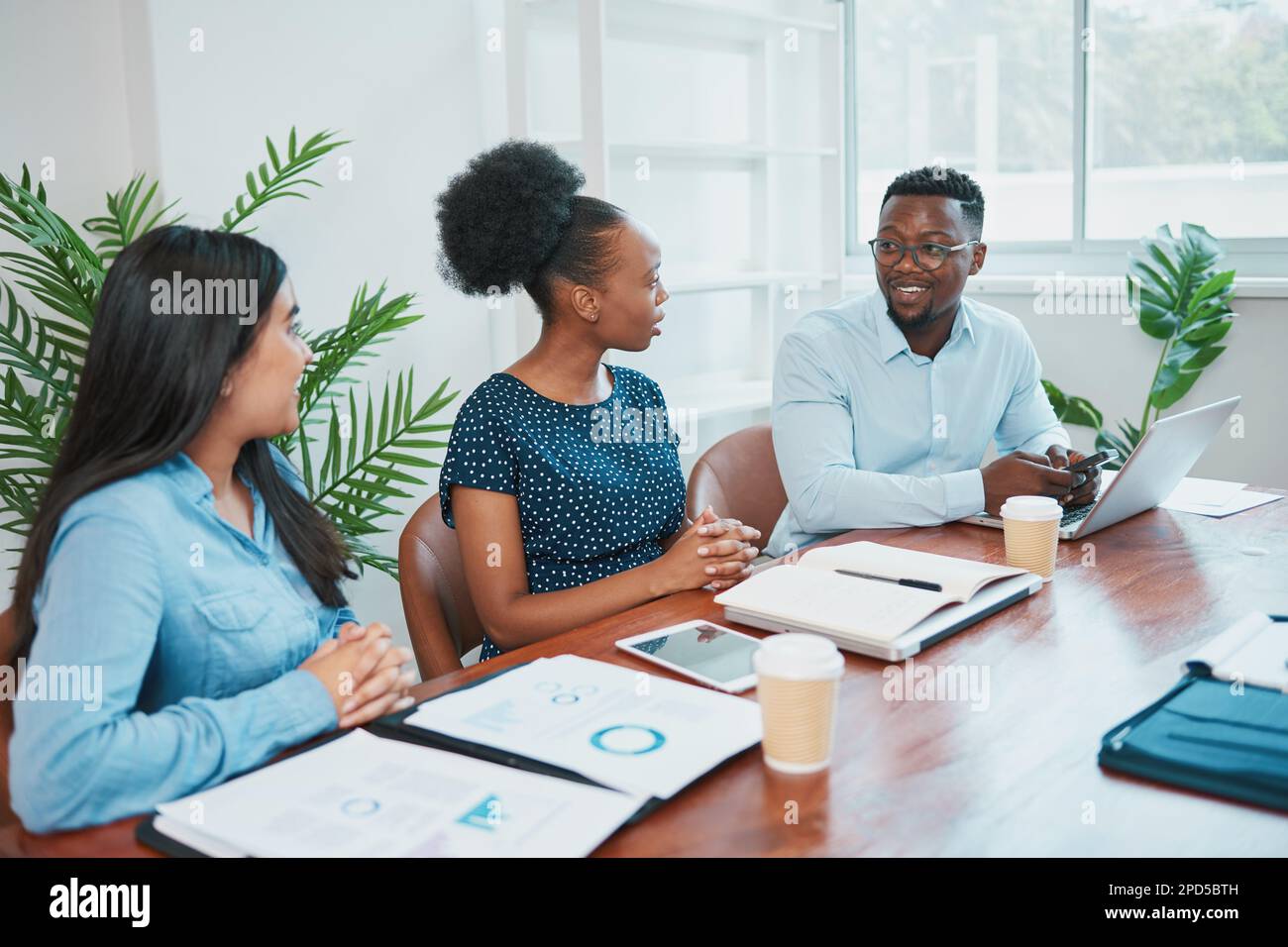 Three diverse colleagues discuss financials at boardroom table in ...