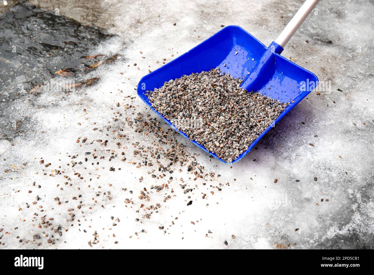 Gravel used on slippery streets roads. Person scattering gravel sand on ...