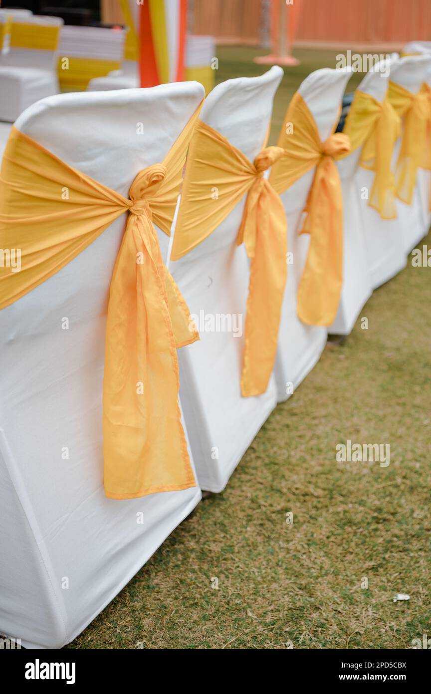 An organized arrangement of white and yellow-decorated chairs, lined up ...