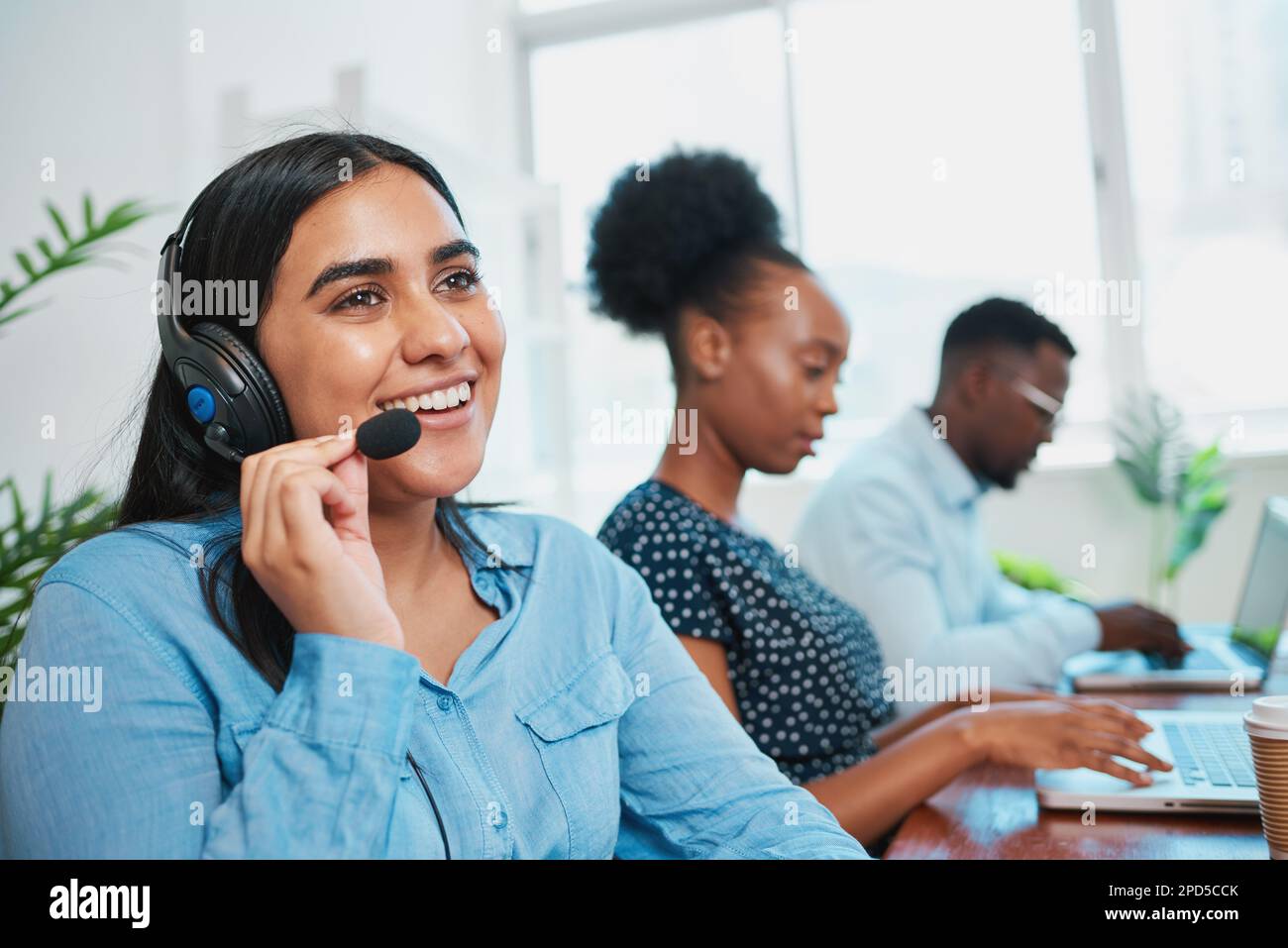 A friendly South Asian woman talks to client on headset, support agent ...