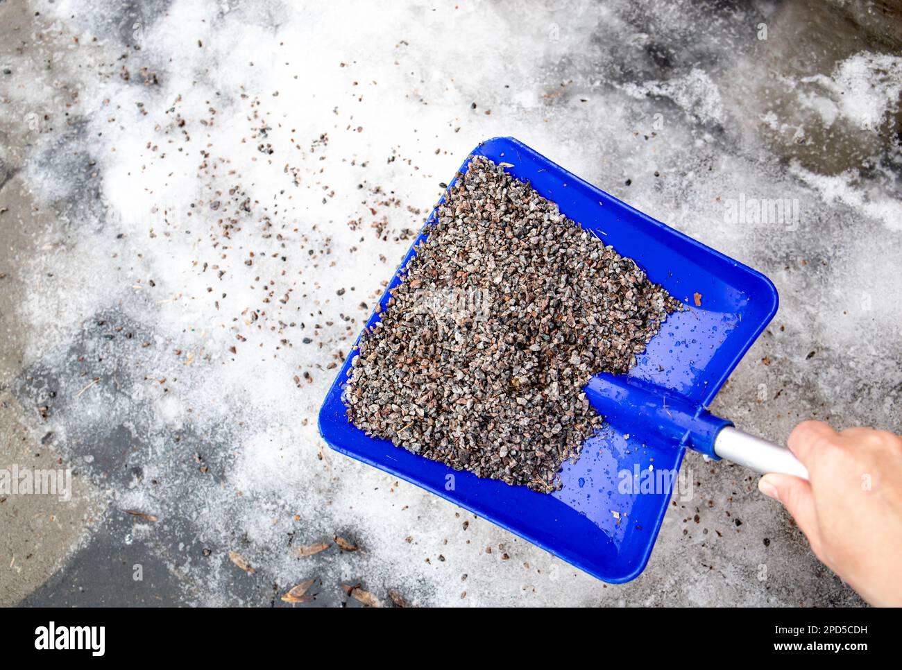 Gravel used on slippery streets roads. Person scattering gravel sand on ...