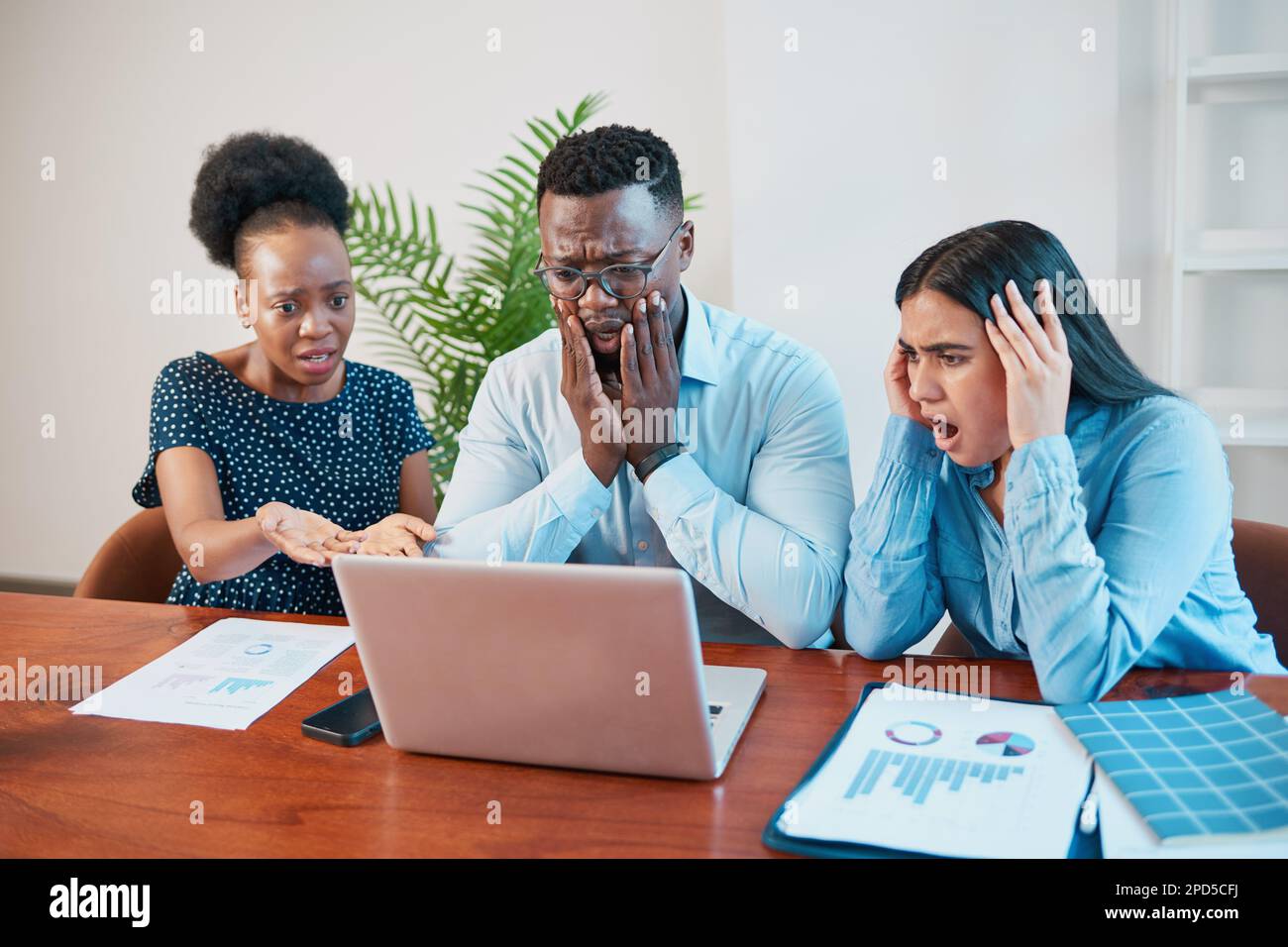 Three colleagues look shocked at laptop screen, project failure, crash ...