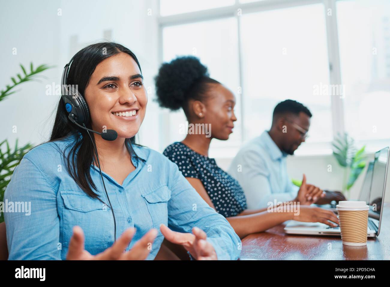 A friendly South Asian woman talks to client on headset, support agent ...
