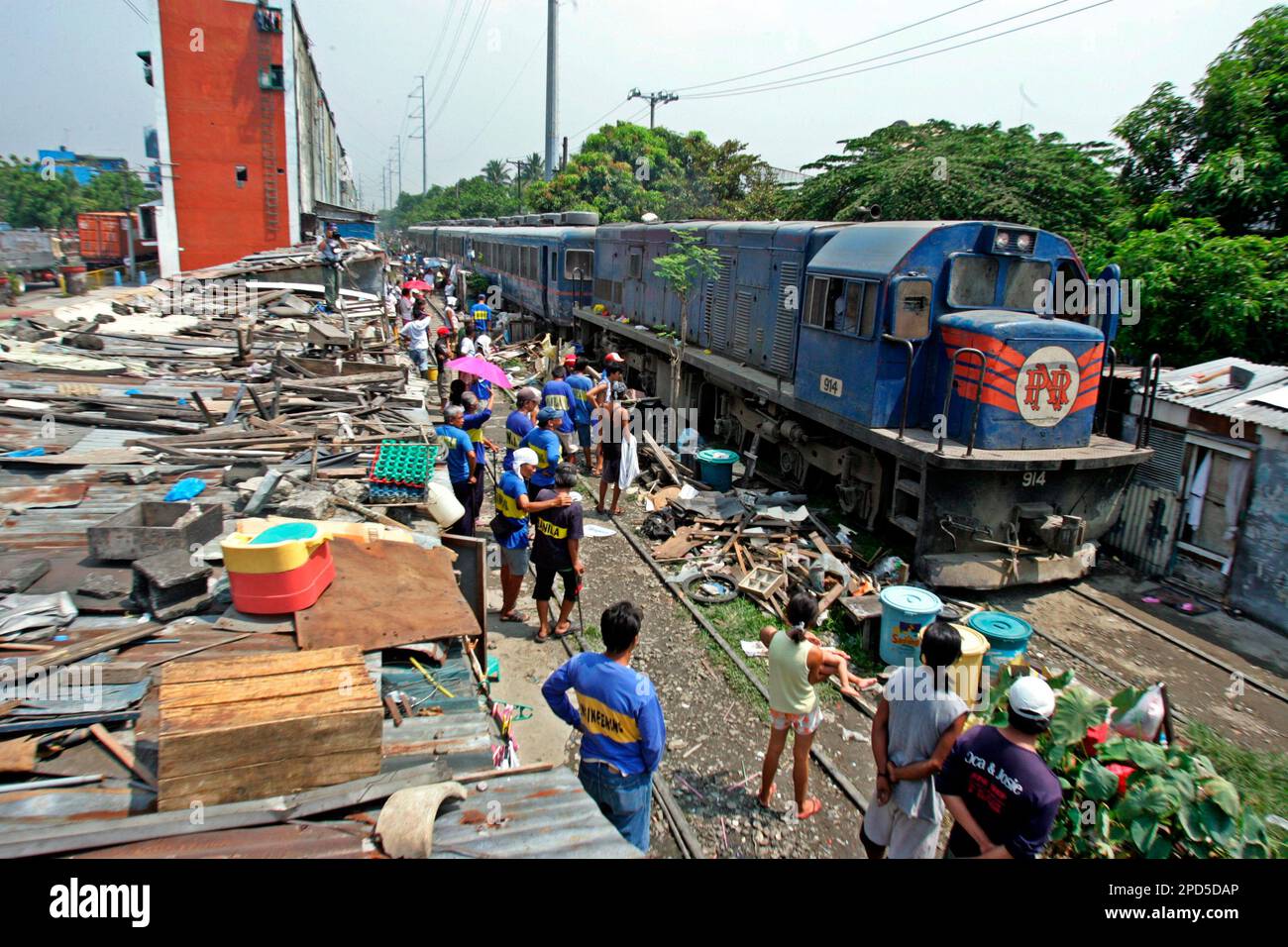 Demolition crew and squatters pause as a dilapidated train passes by in ...