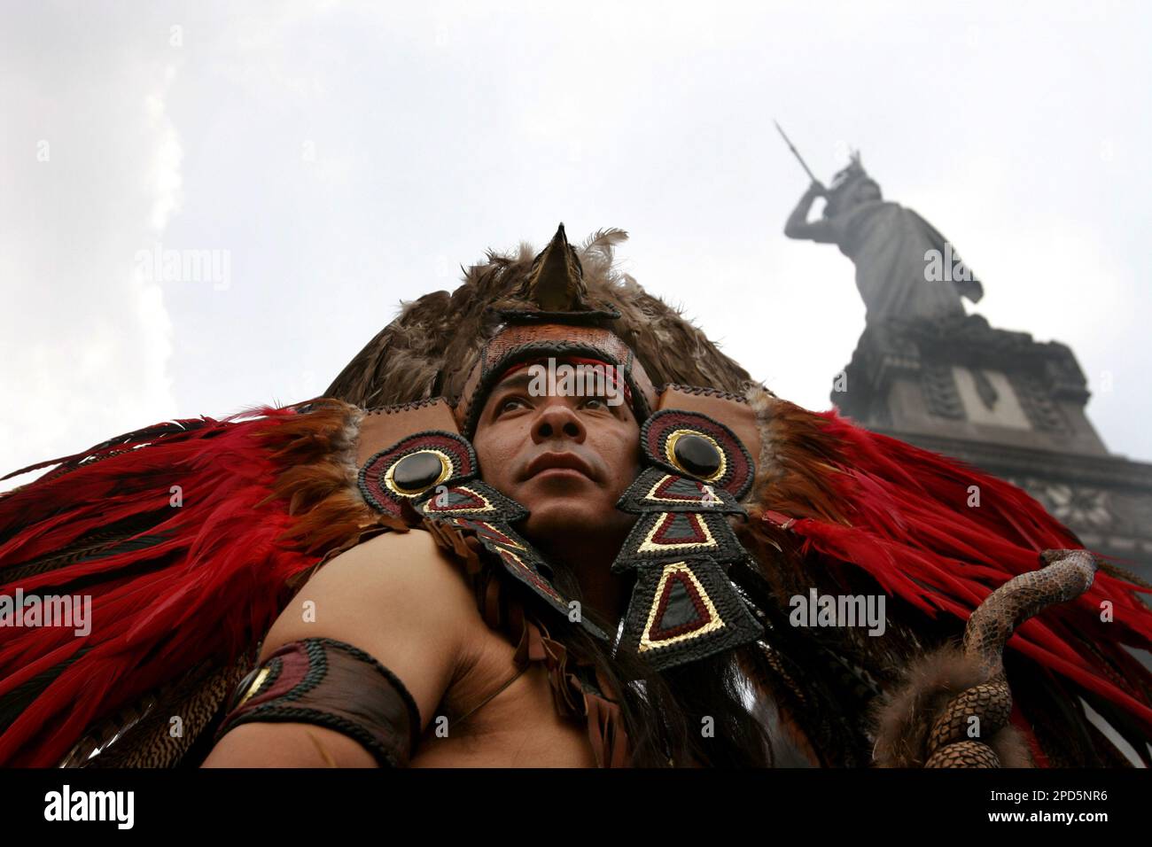 A man dressed in traditional Aztec clothing dances in front of a ...