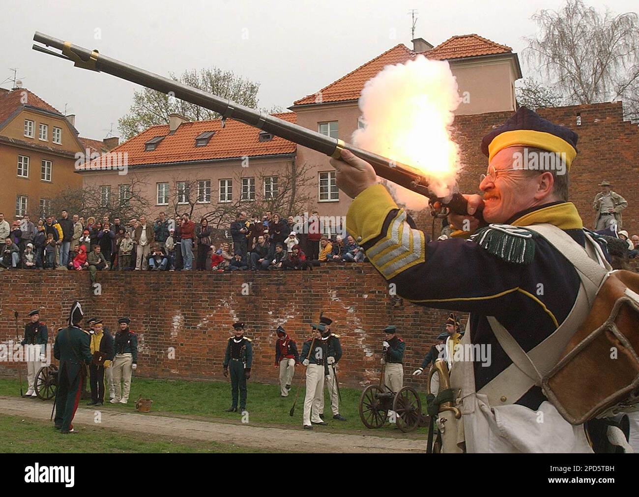 A man dressed as an 18th century soldier fires his musket as spectators ...