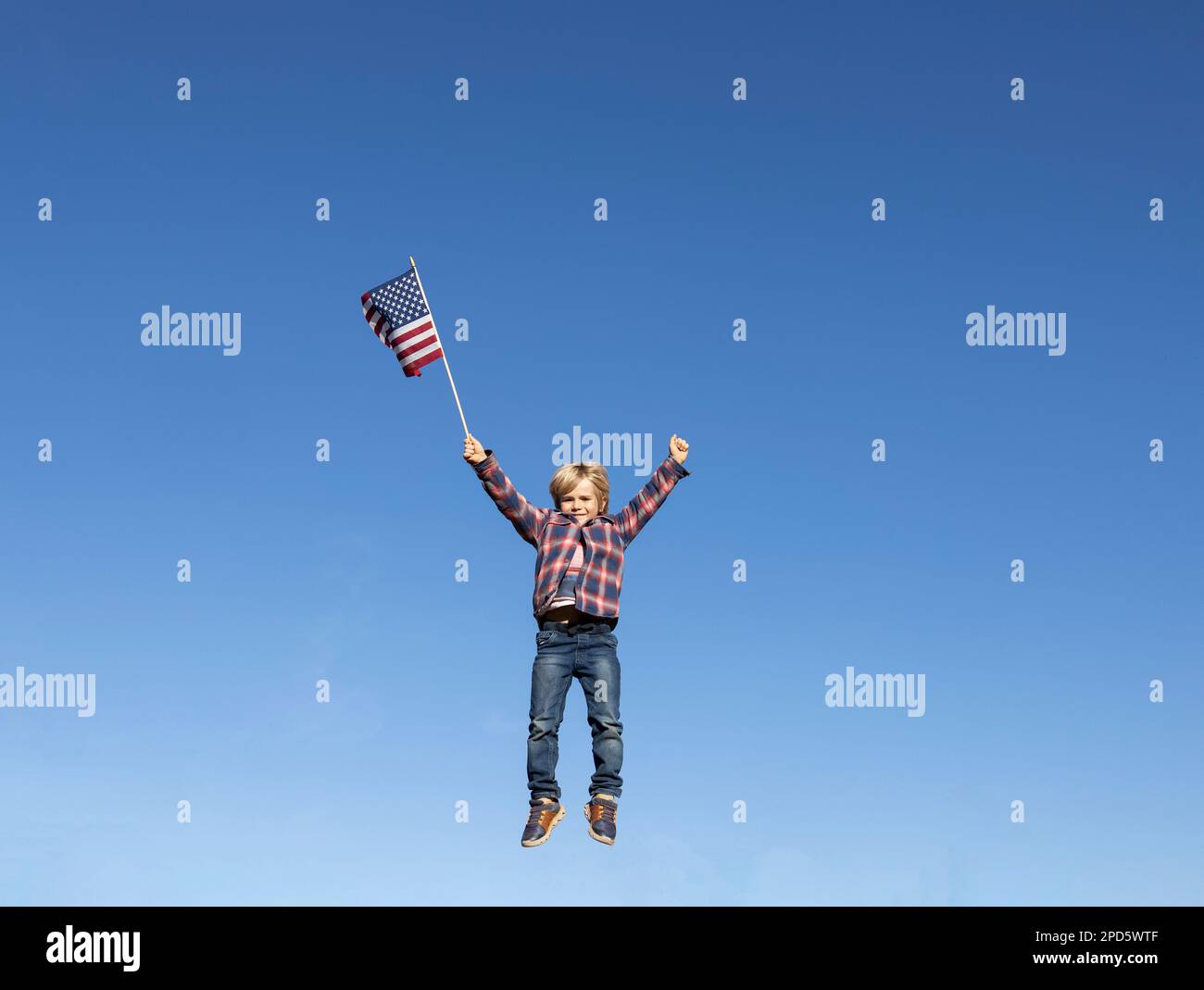 Patriotic boy 6 years old jumps up with the American flag against the ...