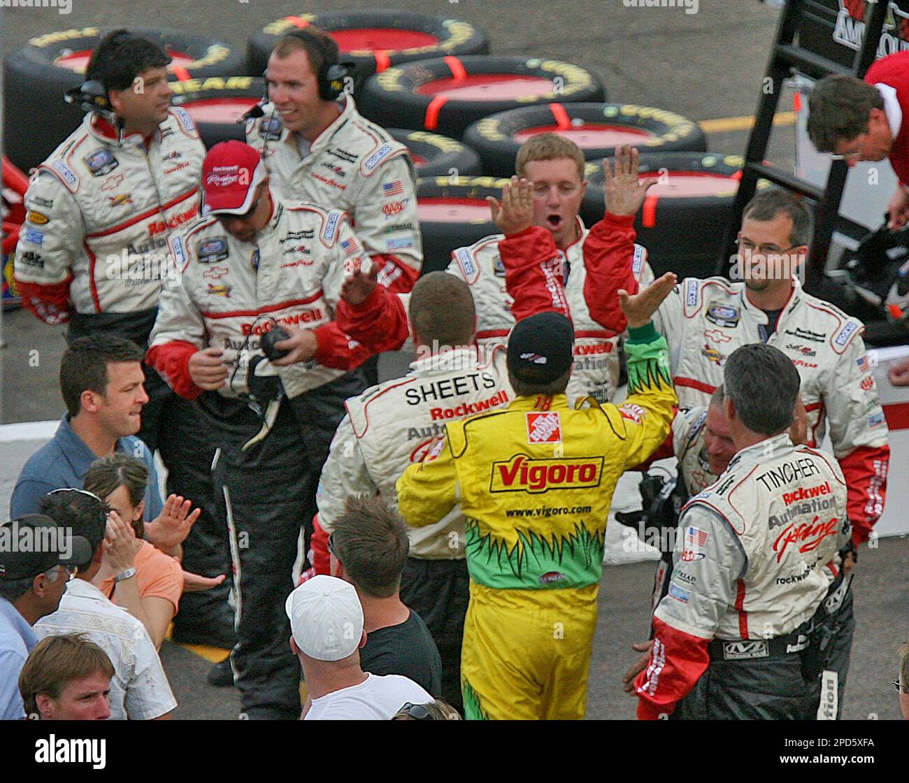 J.J. Yeley, in yellow, high fives the crew from Rockwell Automation ...