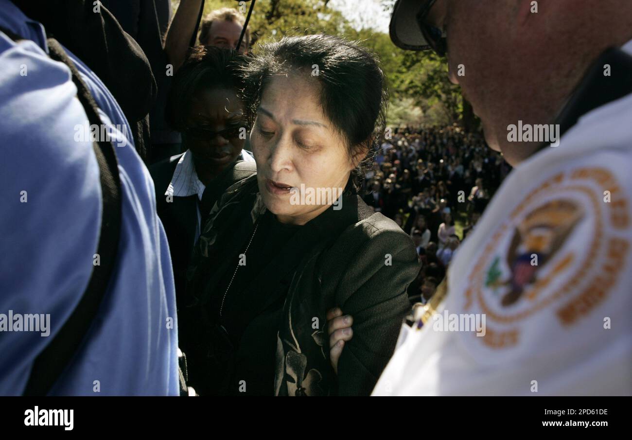 Wenyi Wang, 47, center, is escorted from the camera stand by Secret ...