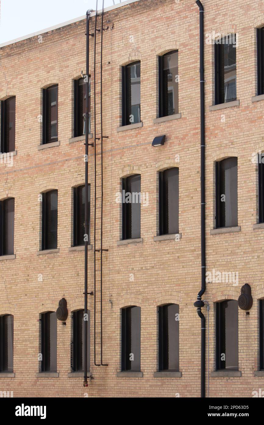The exterior side of a four story brown brick building with a fire ...