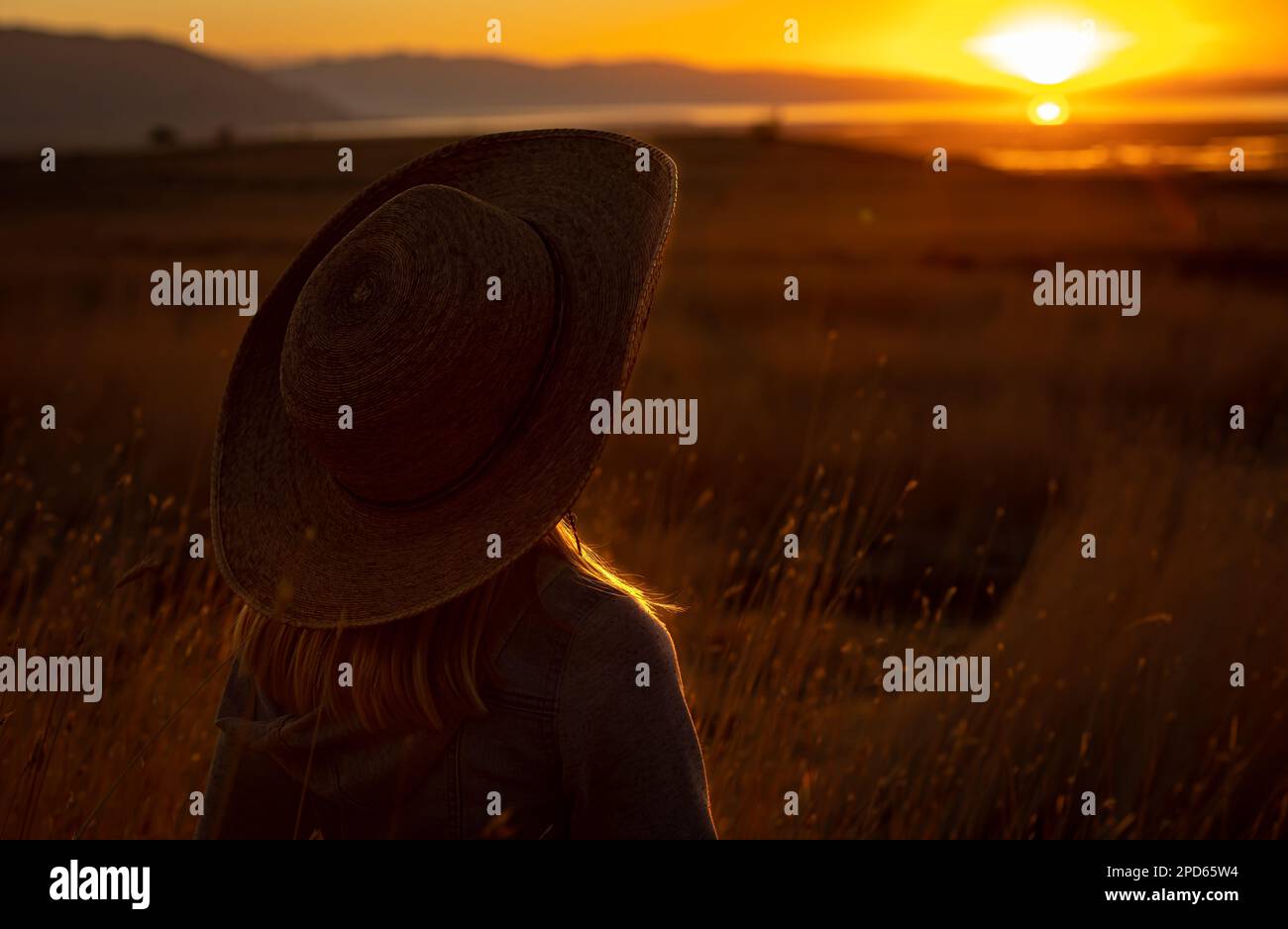 Backside of a little girl who is wearing a straw cowboy hat and ...