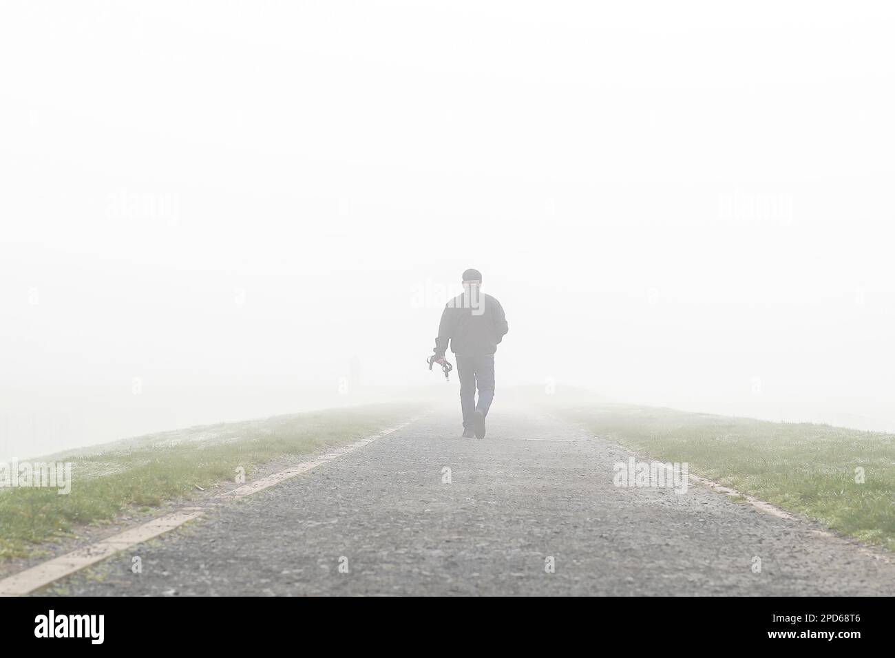Rear view of isolated man walking down a long path disappearing into ...