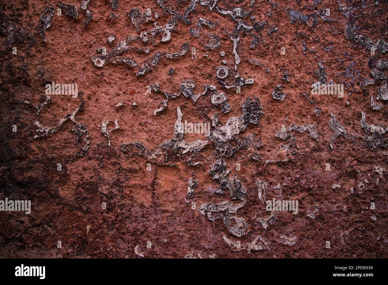 The texture of an old rustic wall is covered with red stucco. Abstract ...