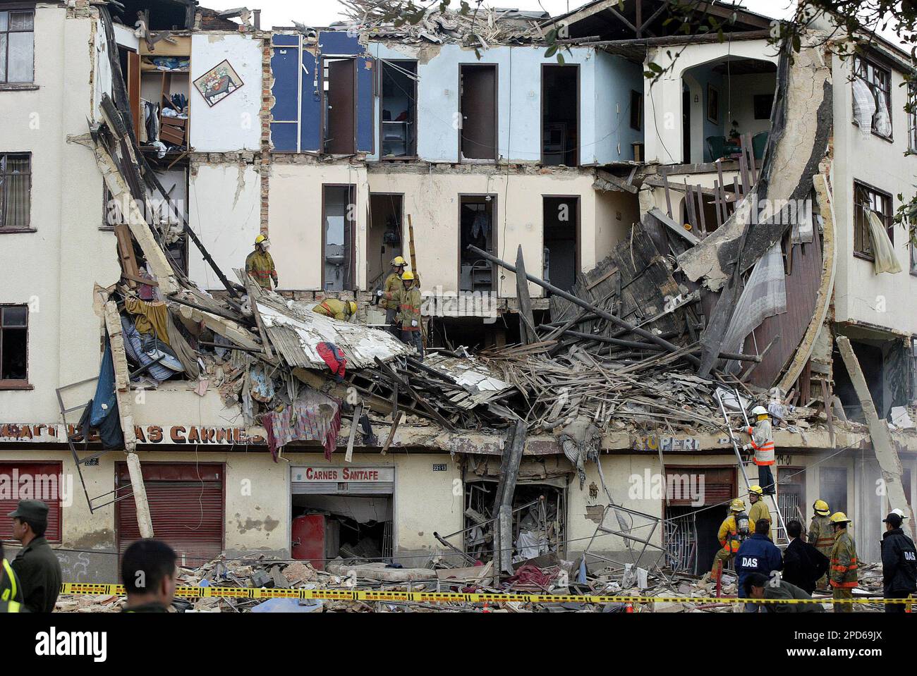 Fire fighters and police officers search the remains of a building ...