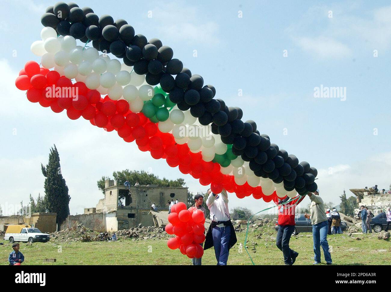 Syrians hold a red, white and black Syrian flag made of balloons while ...