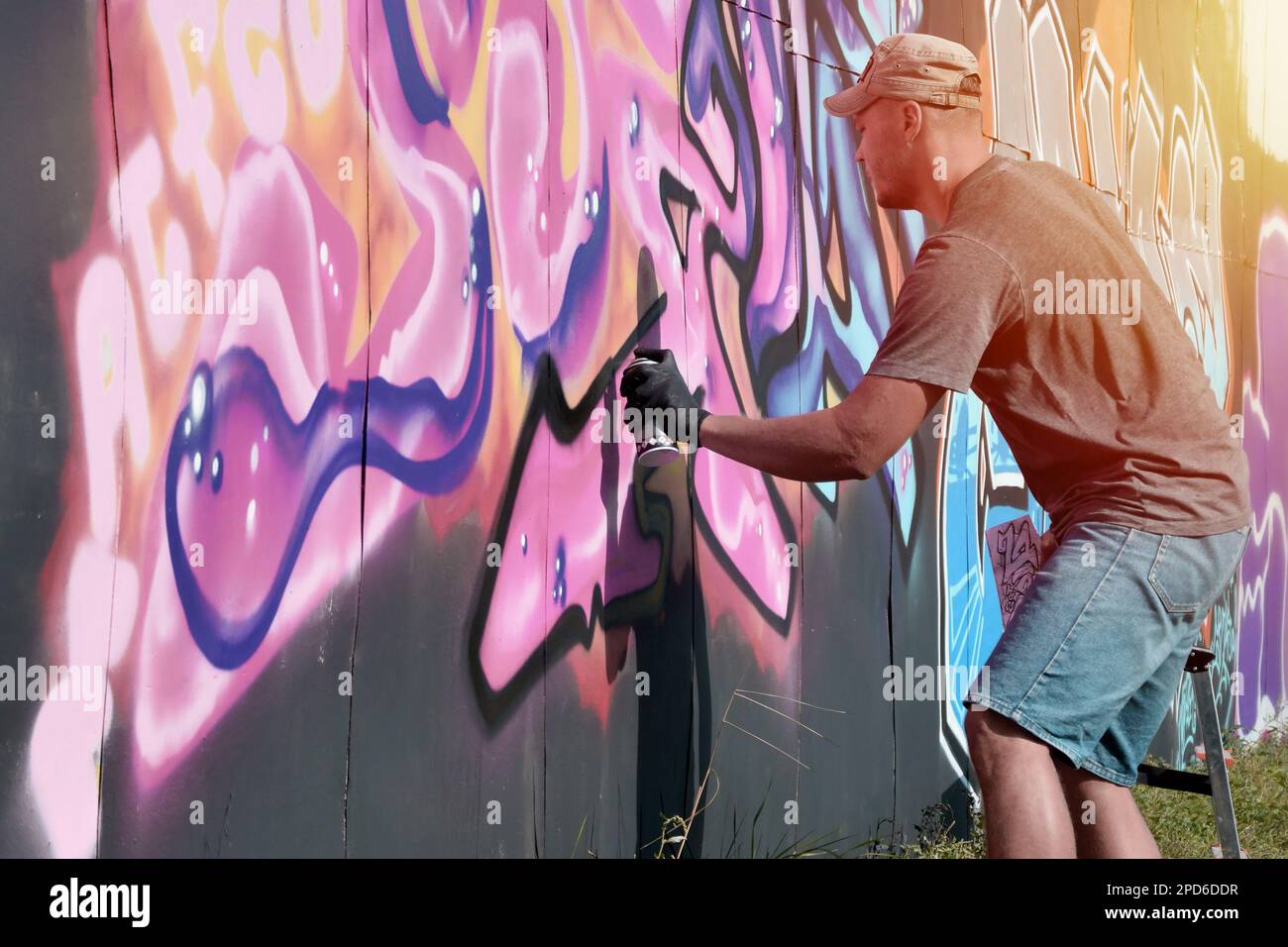 Young caucasian male graffiti artist drawing big street art painting in ...