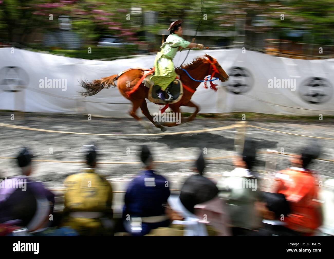 A mounted archer in a Samurai warrior costume sets up an arrow and bow ...