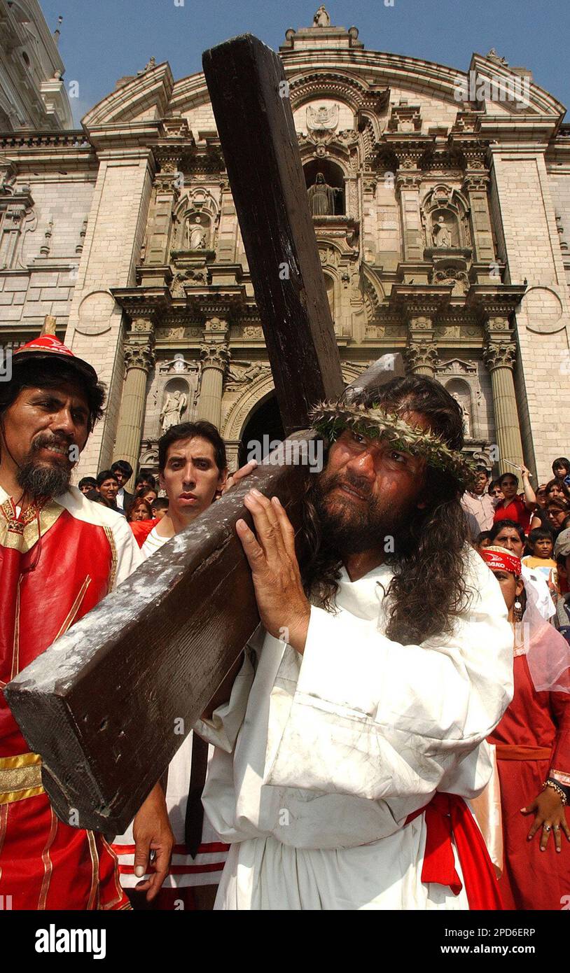 A penitent portraying Jesus is seen carrying a cross during an ...