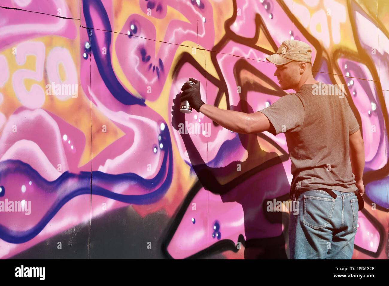 Young caucasian male graffiti artist drawing big street art painting in ...