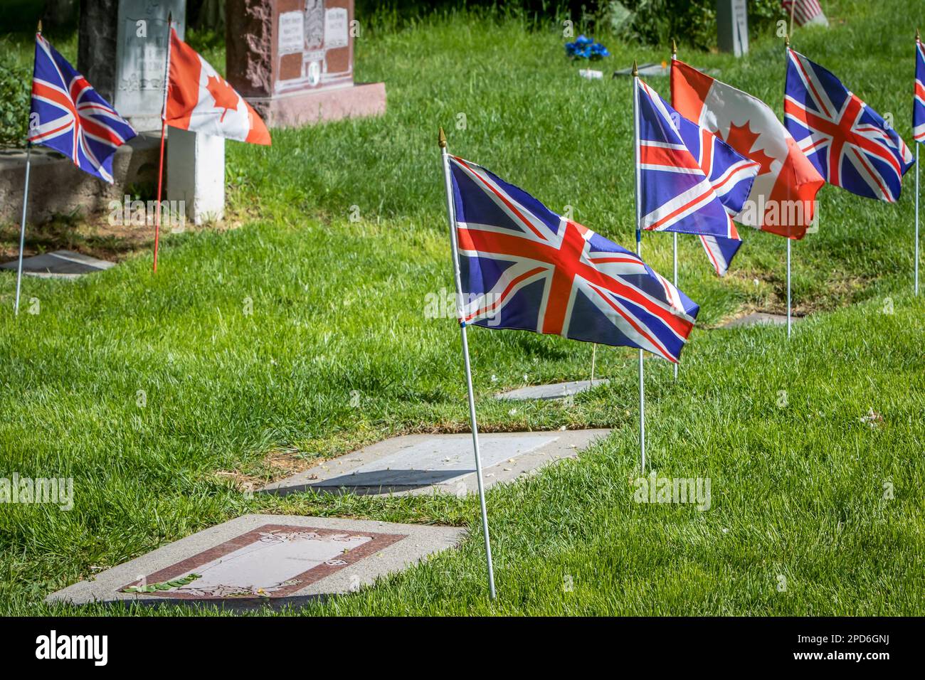 Flags of Canada and Great Britain decorating headstones at a cemetery ...