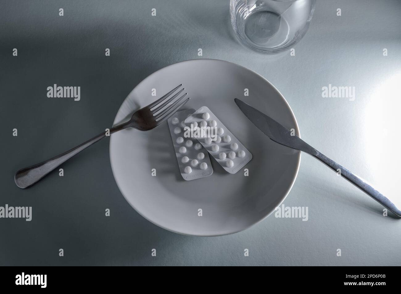 plate with blister packs of medicine pills, fork and knife - concept ...