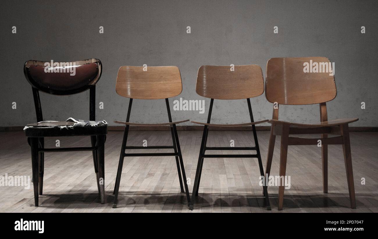 Four old worn wooden and metal chairs in a row on a theater stage Stock ...