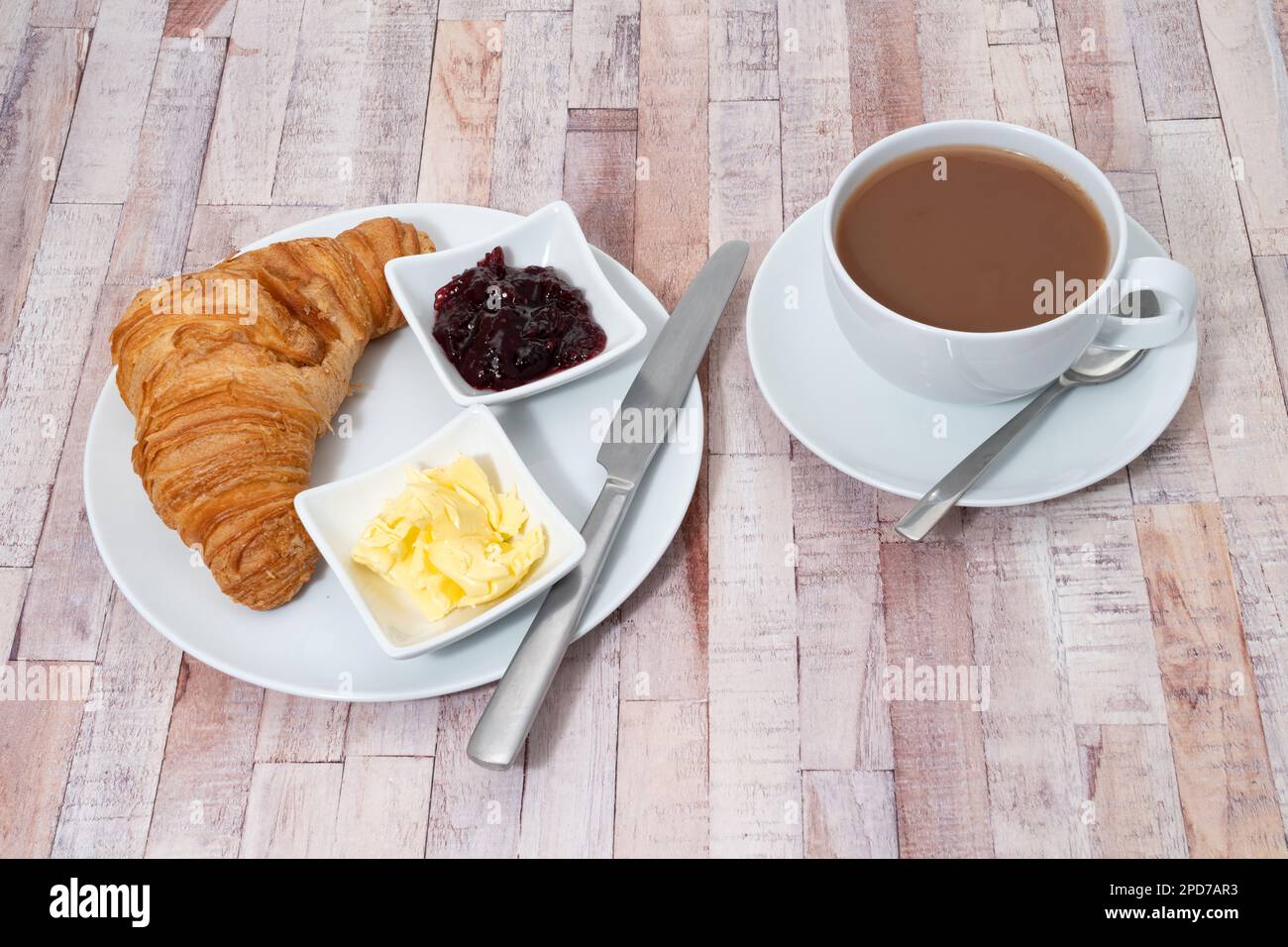 Breakfast items of a fresh croissant with dairy butter and raspberry ...