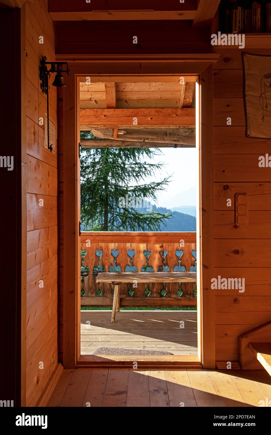 view through open door of wooden alpine hut towards carved wooden ...