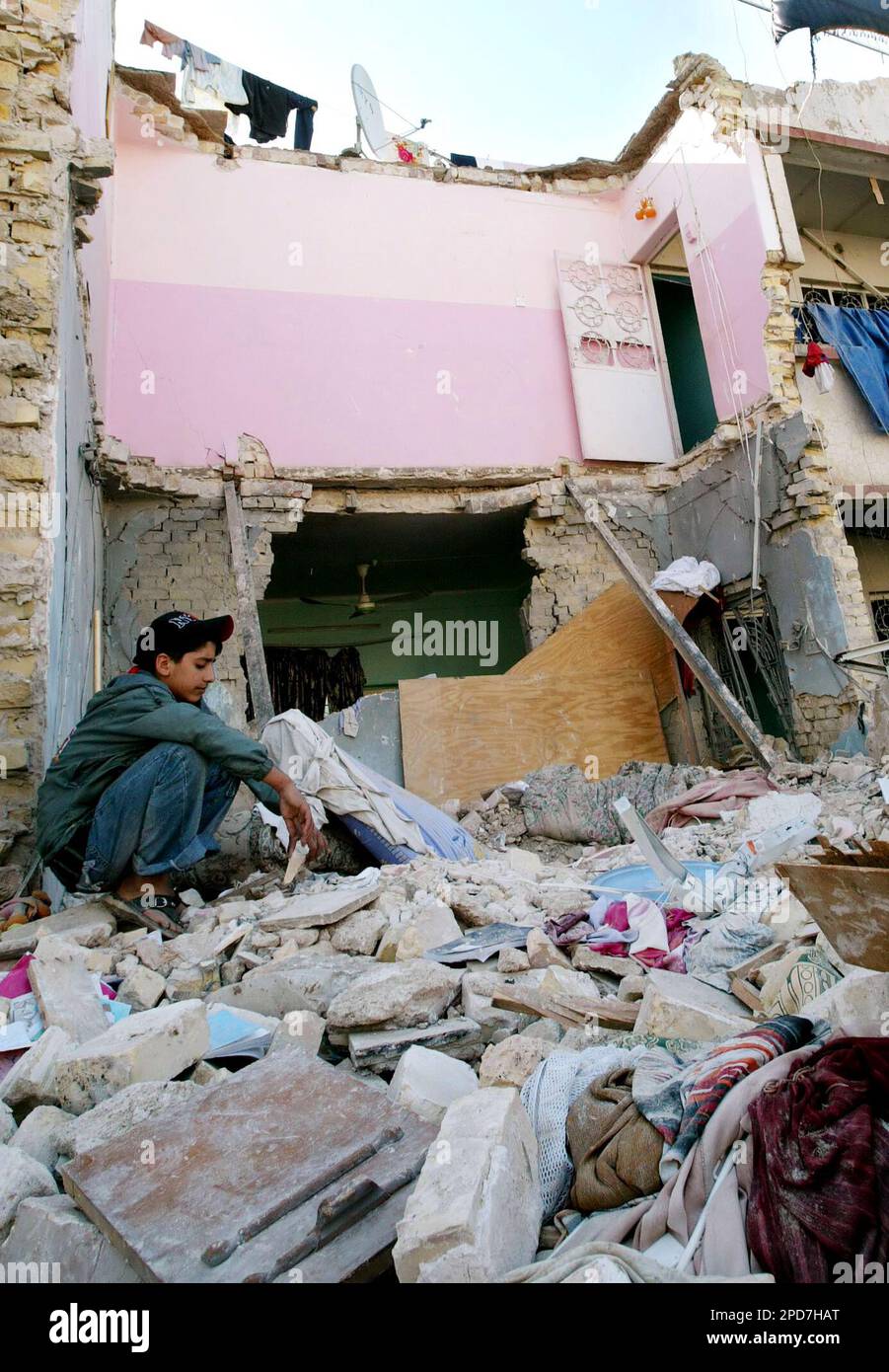 An Iraqi boy sits in the wreckage of a house destroyed by a bomb which ...