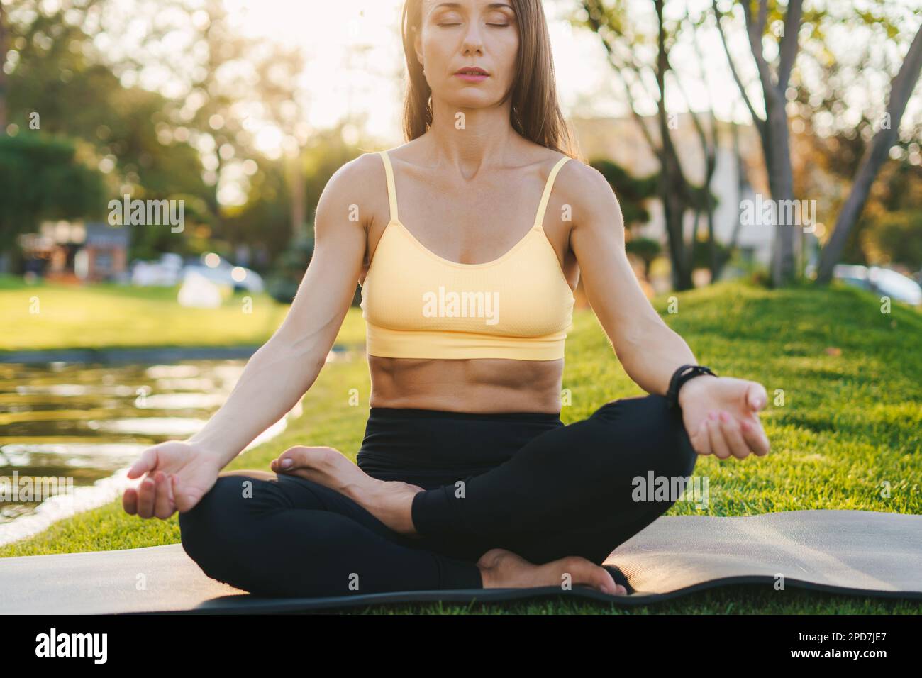 Front view portrait of a young brunette caucasian woman sitting on yoga ...