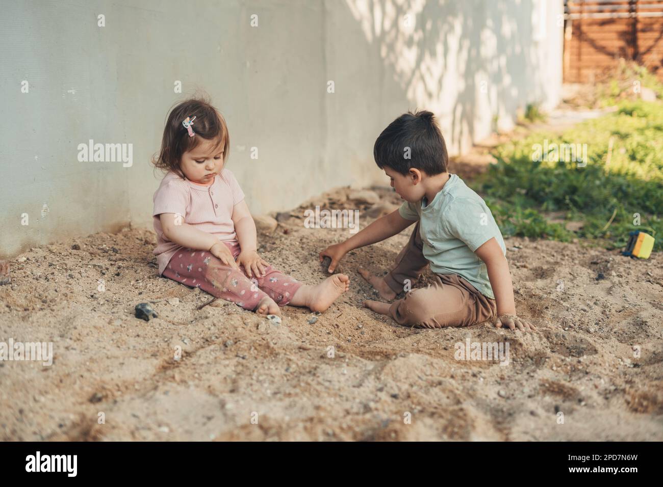Adorable little child boy and baby sister observing, exploring sand and ...