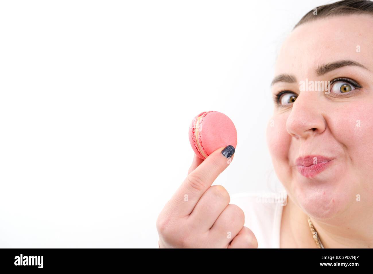 Cheerful beautiful girl eating macaroon with eyes closed isolated over ...