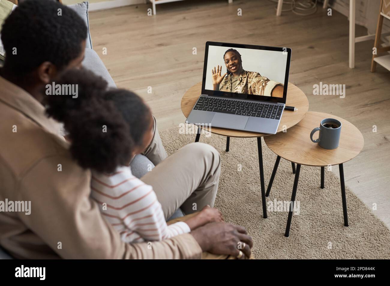 Military woman waving her family from the screen of laptop during video ...