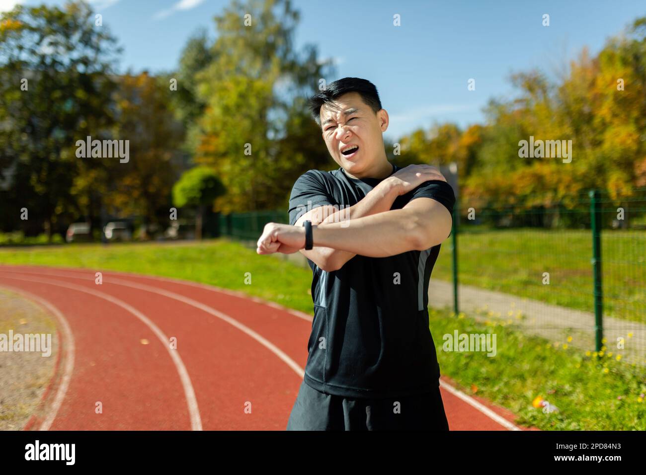 Asian sportsman stretches his shoulder, man in the stadium after ...