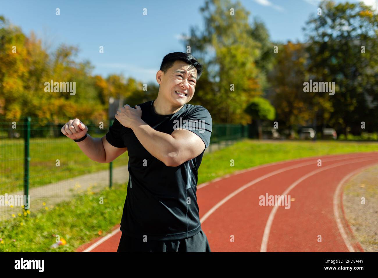 Asian sportsman stretches his shoulder, man in the stadium after ...