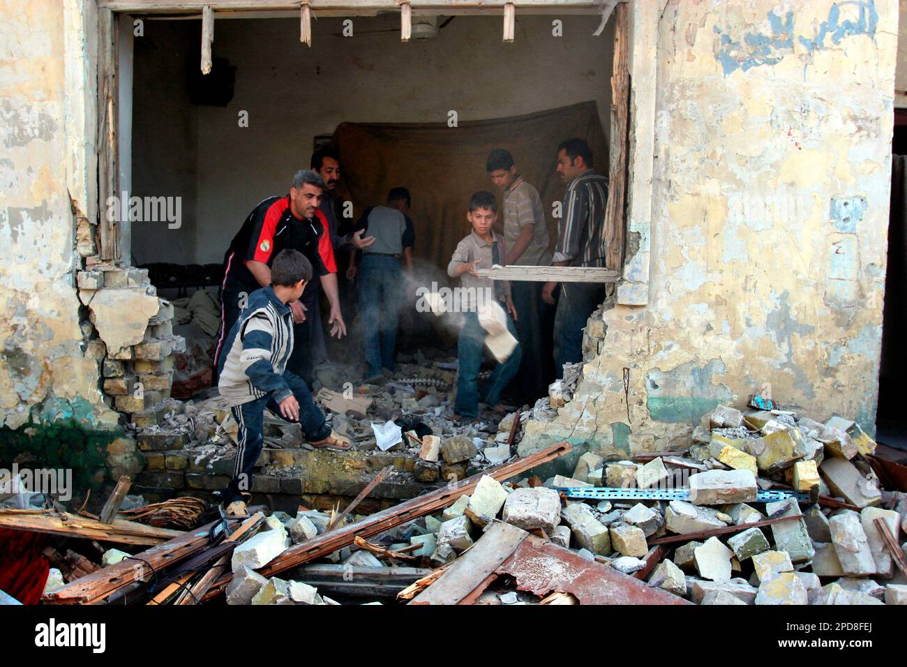 Iraqi men clean the debris of their damaged house, following a bomb ...