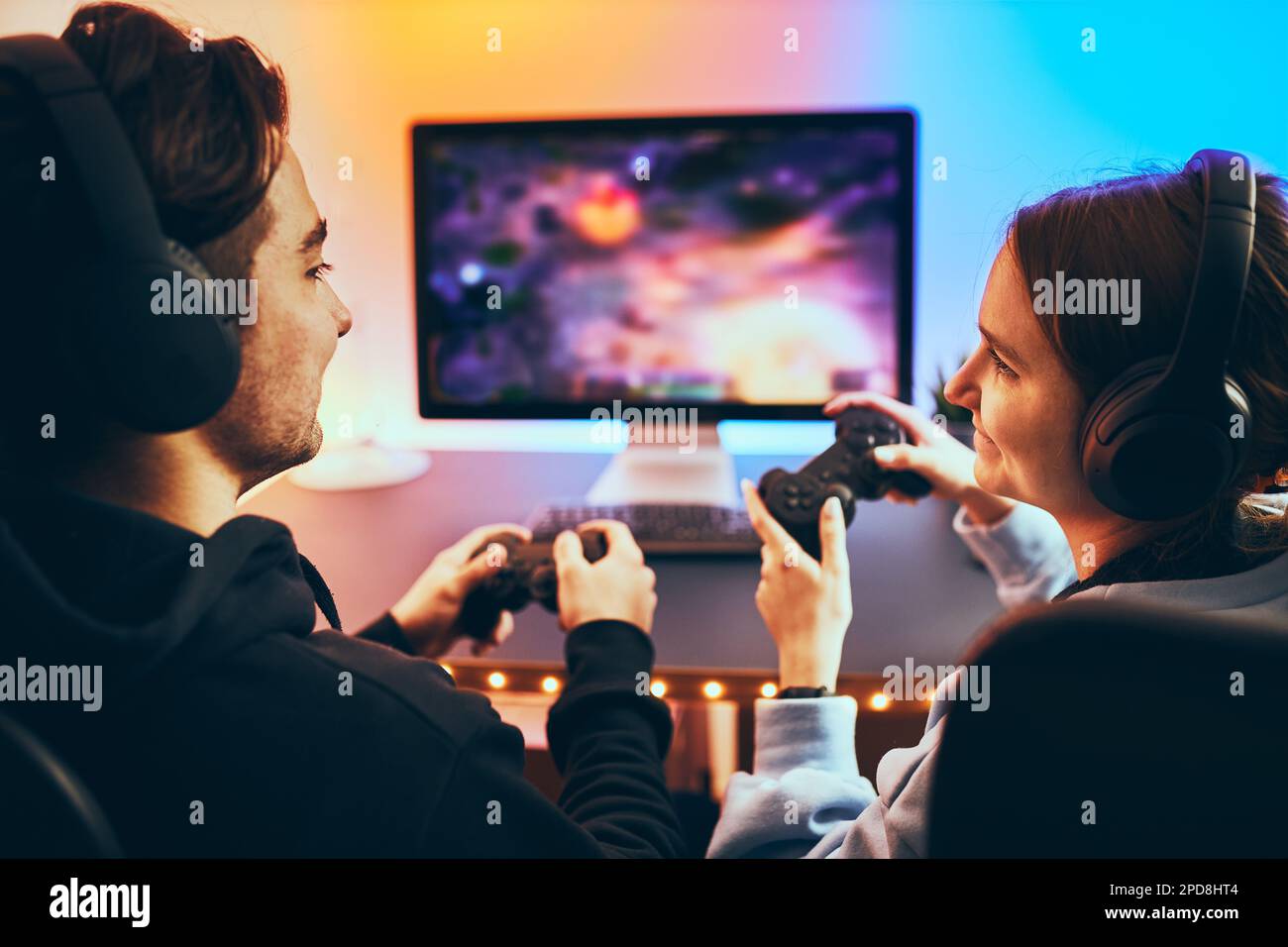 Friends playing video game at home. Gamers holding gamepads sitting at ...