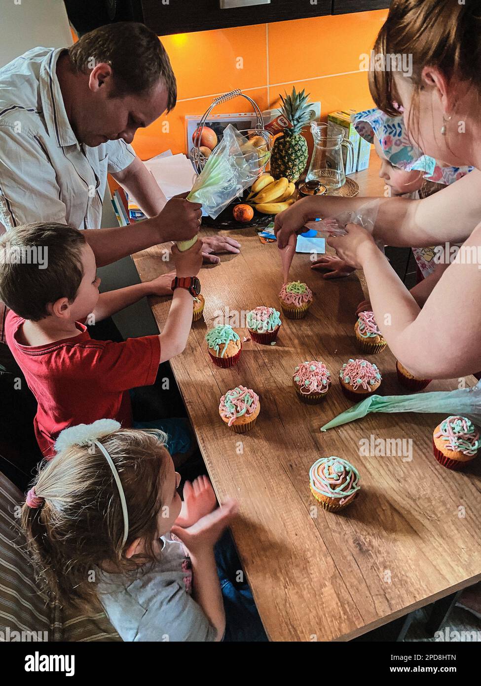 Group of children baking cupcakes, squeezing cream from confectionery ...