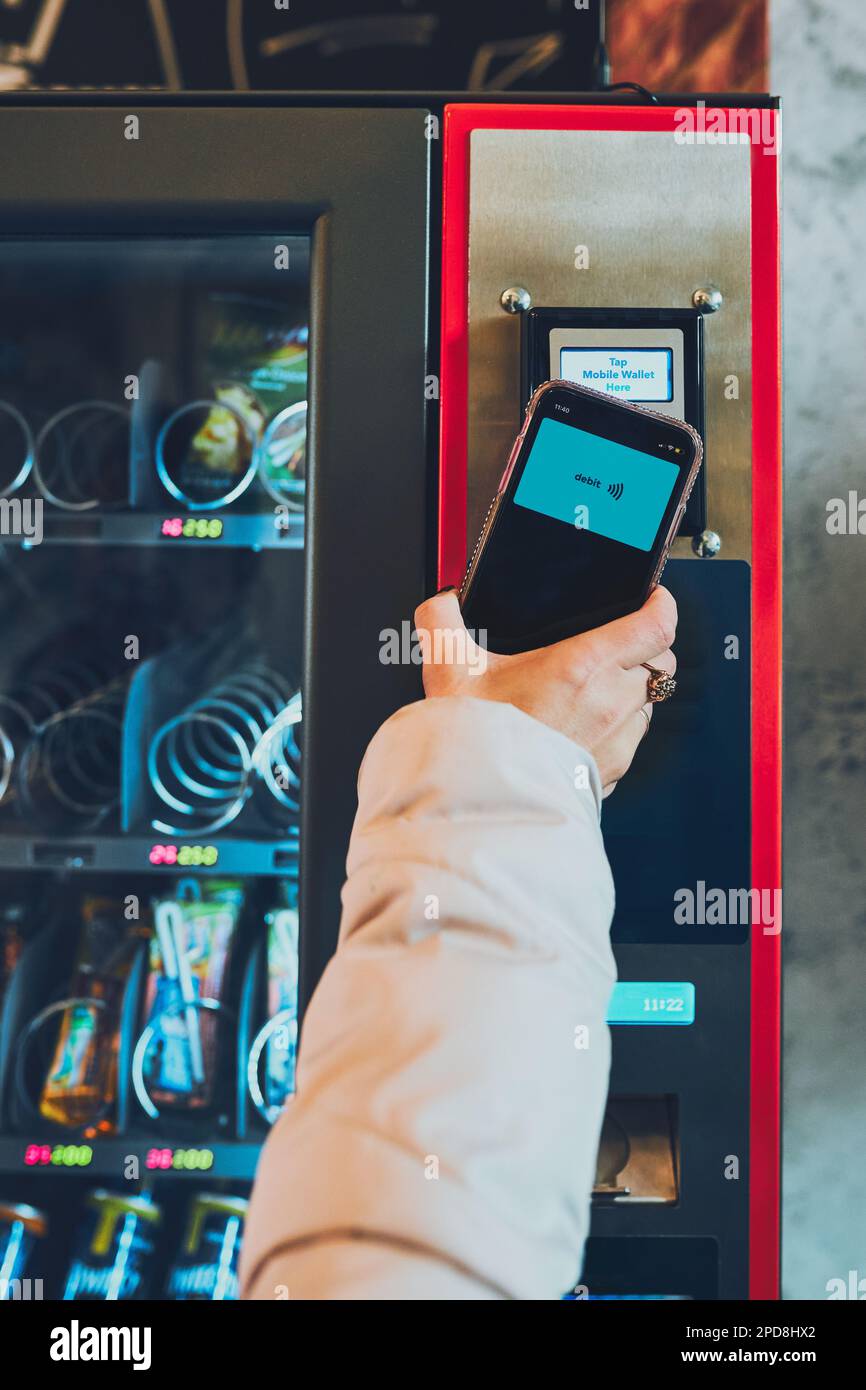 Woman paying for product at vending machine using contactless method of ...