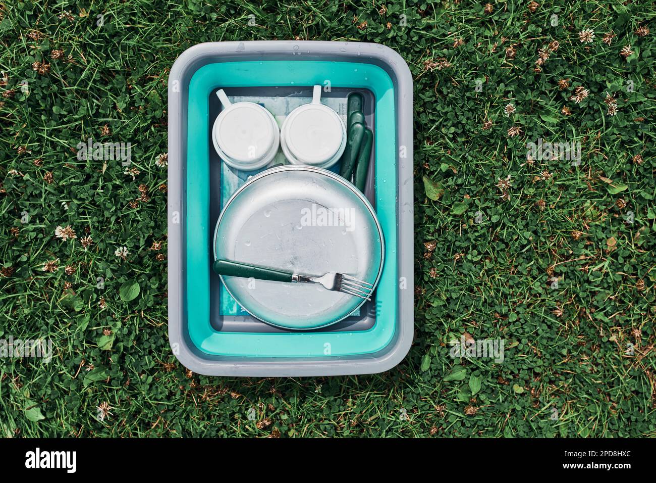 Washing up bowl filled with the washed outdoor dishes, plates, cups and ...